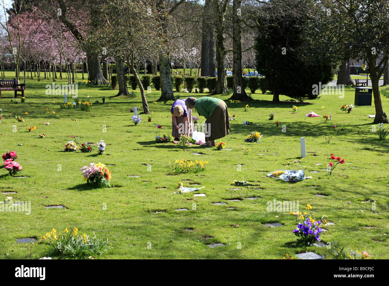 People tending the grave of their family member with fresh flowers at a ...