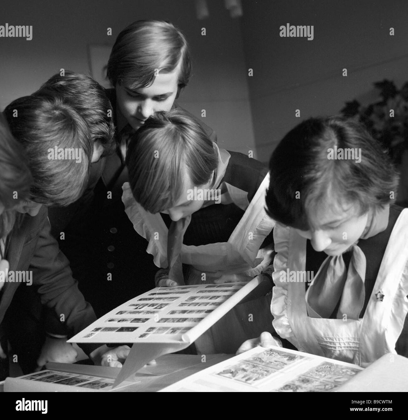 Young stamp collectors scrutinizing stamps Stock Photo - Alamy