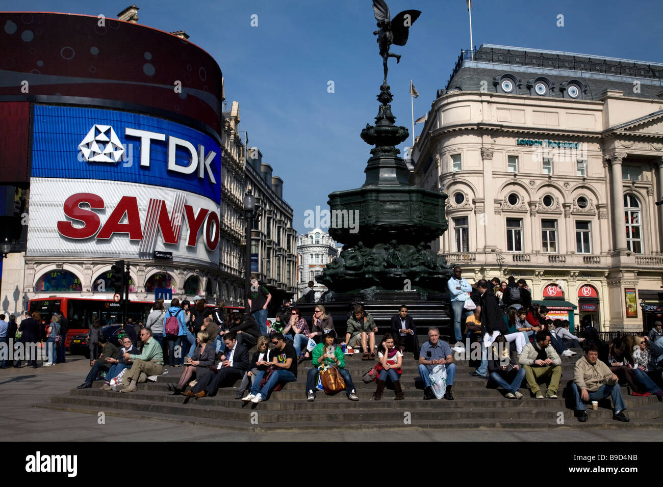 Tourists in Piccadilly Circus sitting on steps around Eros Statue ...