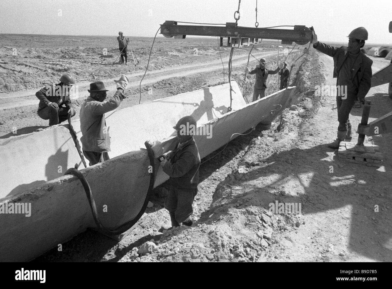 Workers laying concrete chutes at the construction of irrigation canals ...