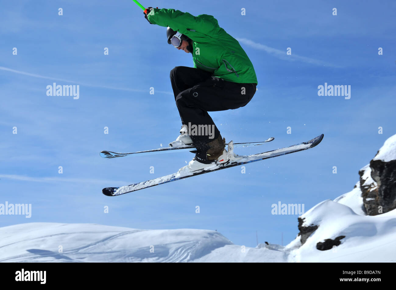 a skier dressed in green and black performing a high jump Stock Photo ...