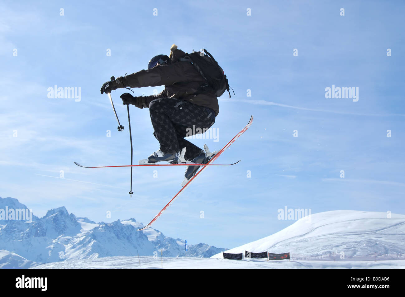 a skier performing a jump and preparing to cross his skis in a classic ...