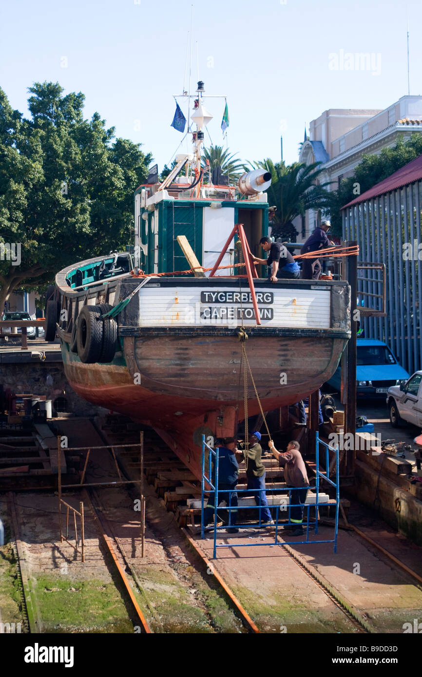 Workers work on the hull of a boat in the V & A Waterfront in Cape Town ...