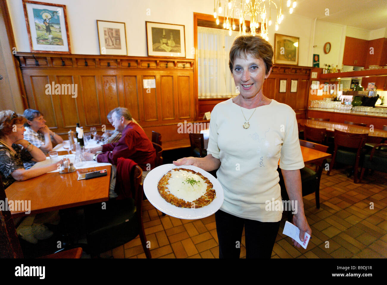 Woman serving the national dish Rosti in the restaurant Hasenburg Old ...