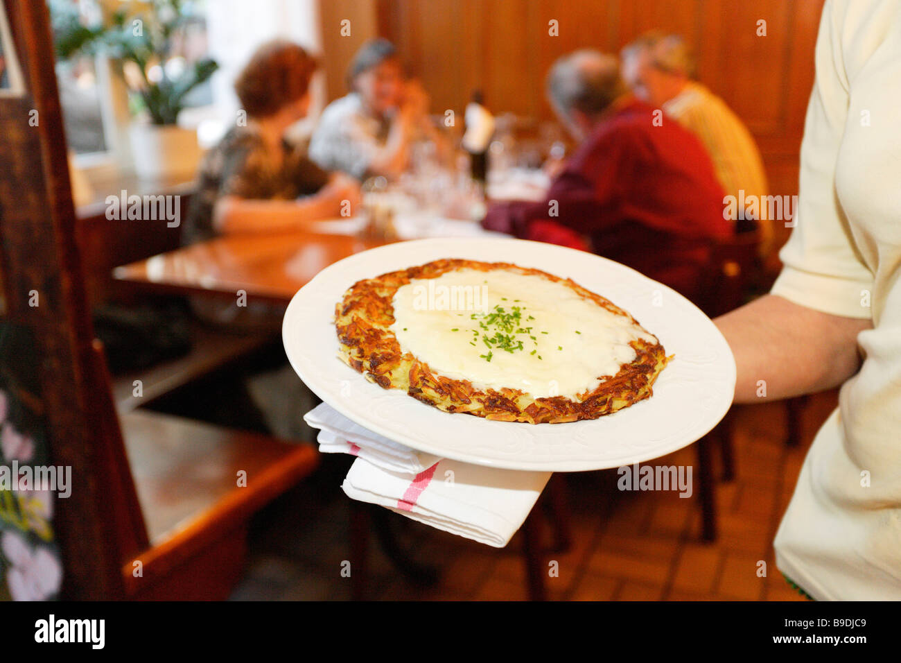 Woman serving the national dish Rosti in the restaurant Hasenburg Old ...