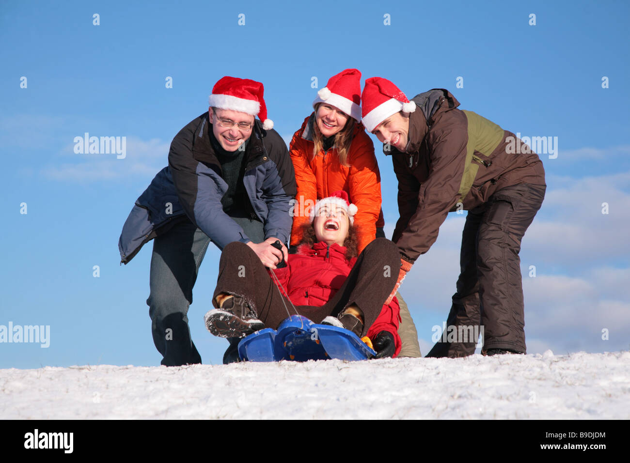 three friends push girl on sled Stock Photo - Alamy