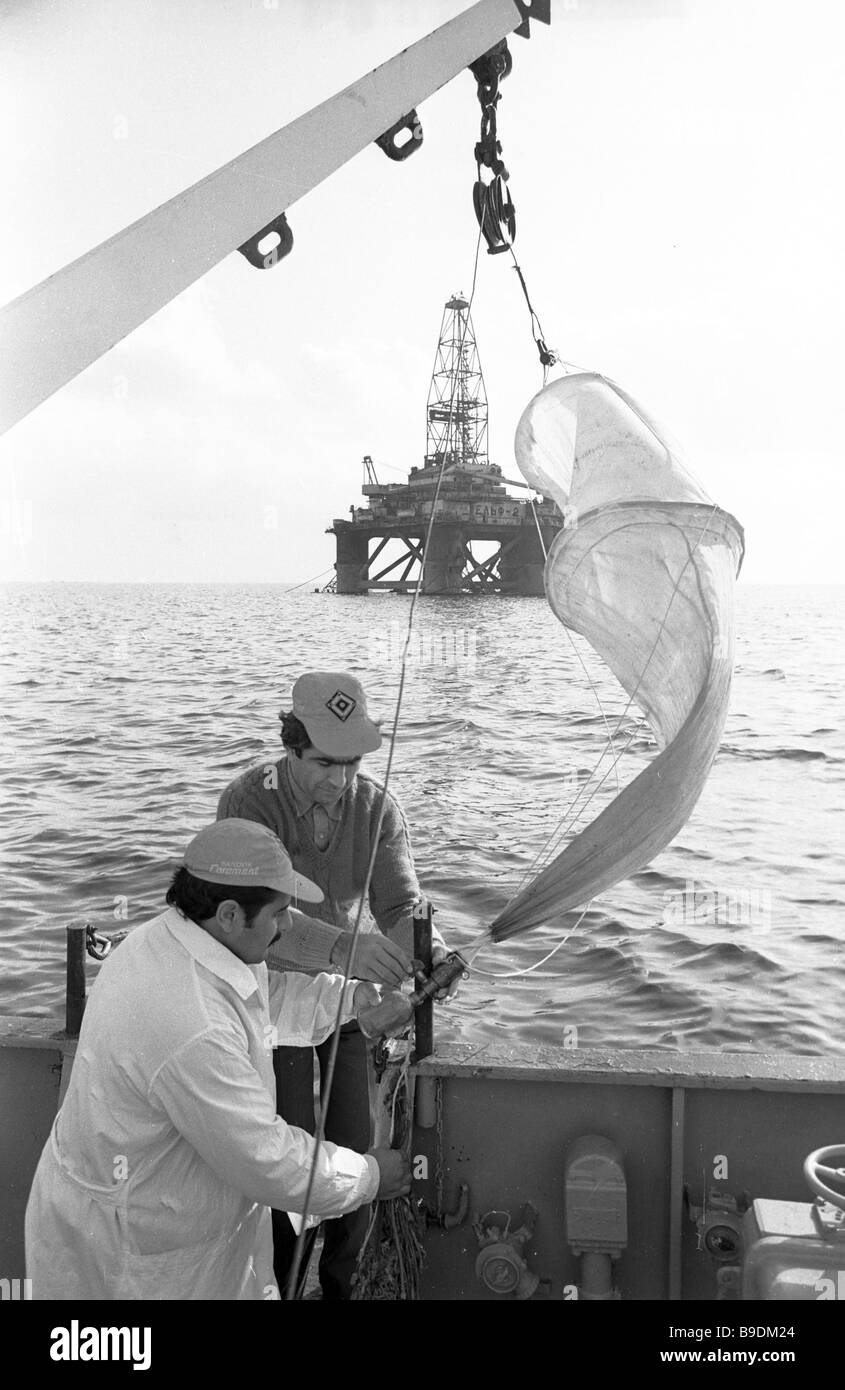 Expedition members aboard a research boat collect plankton on the ...
