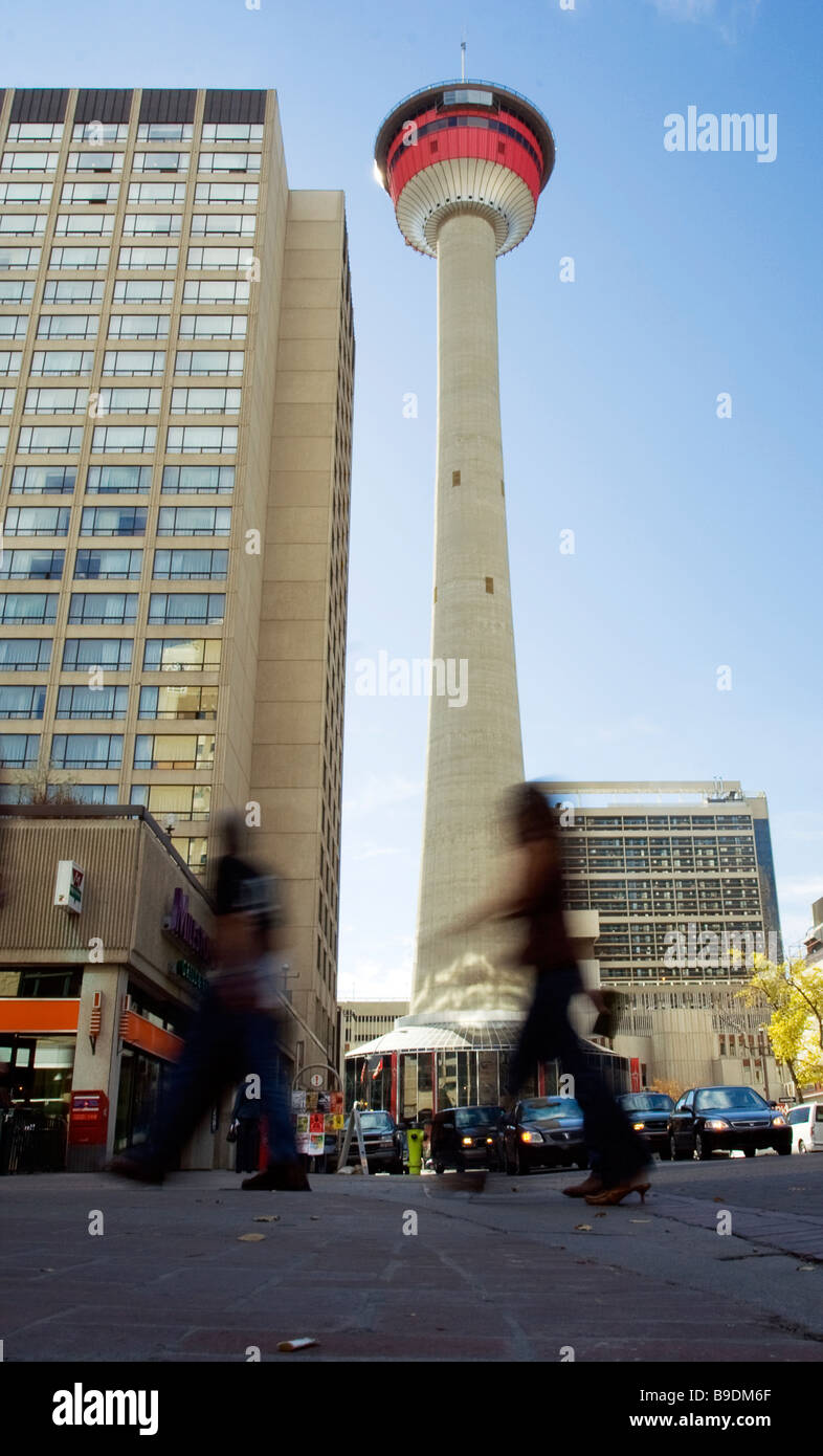 People hurry across the street in downtown with the Calgary Tower in ...