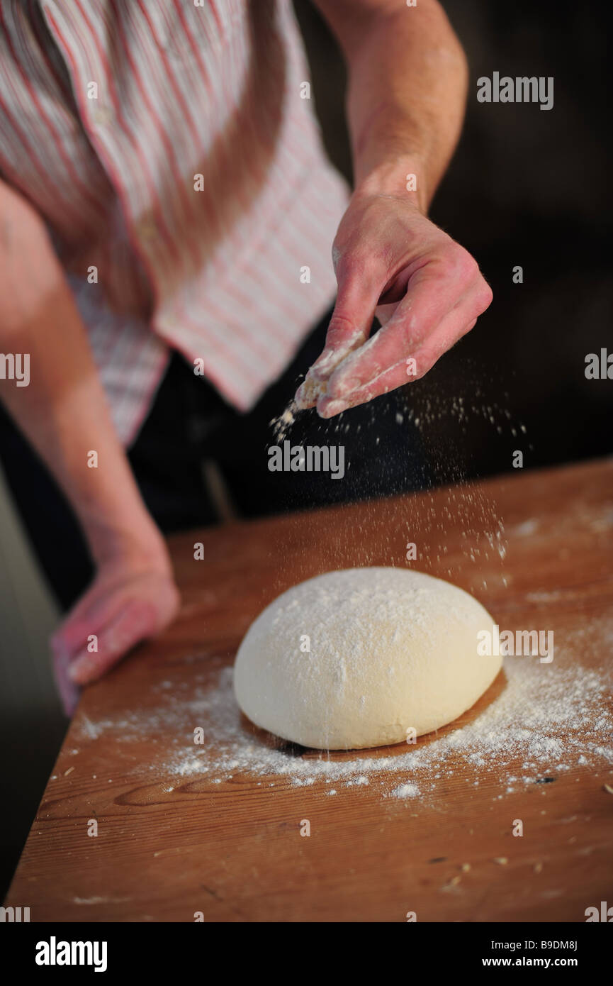 sprinkling flour over fresh dough whilst making bread for the oven on a ...