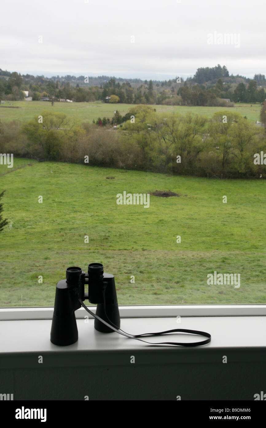 Binoculars sitting on a window ledge overlooking a green field Stock ...