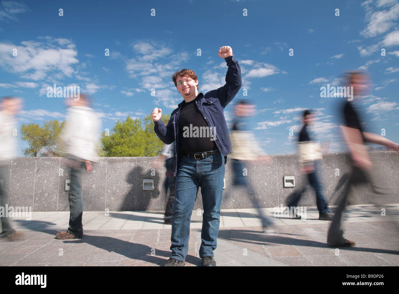 standing man with the lifted hands among moving pedestrians Stock Photo ...