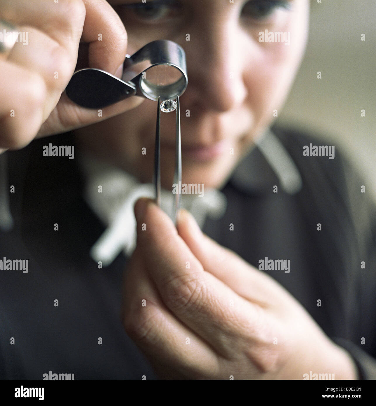 Jewellery factory worker examining diamond with a magnifying glass ...
