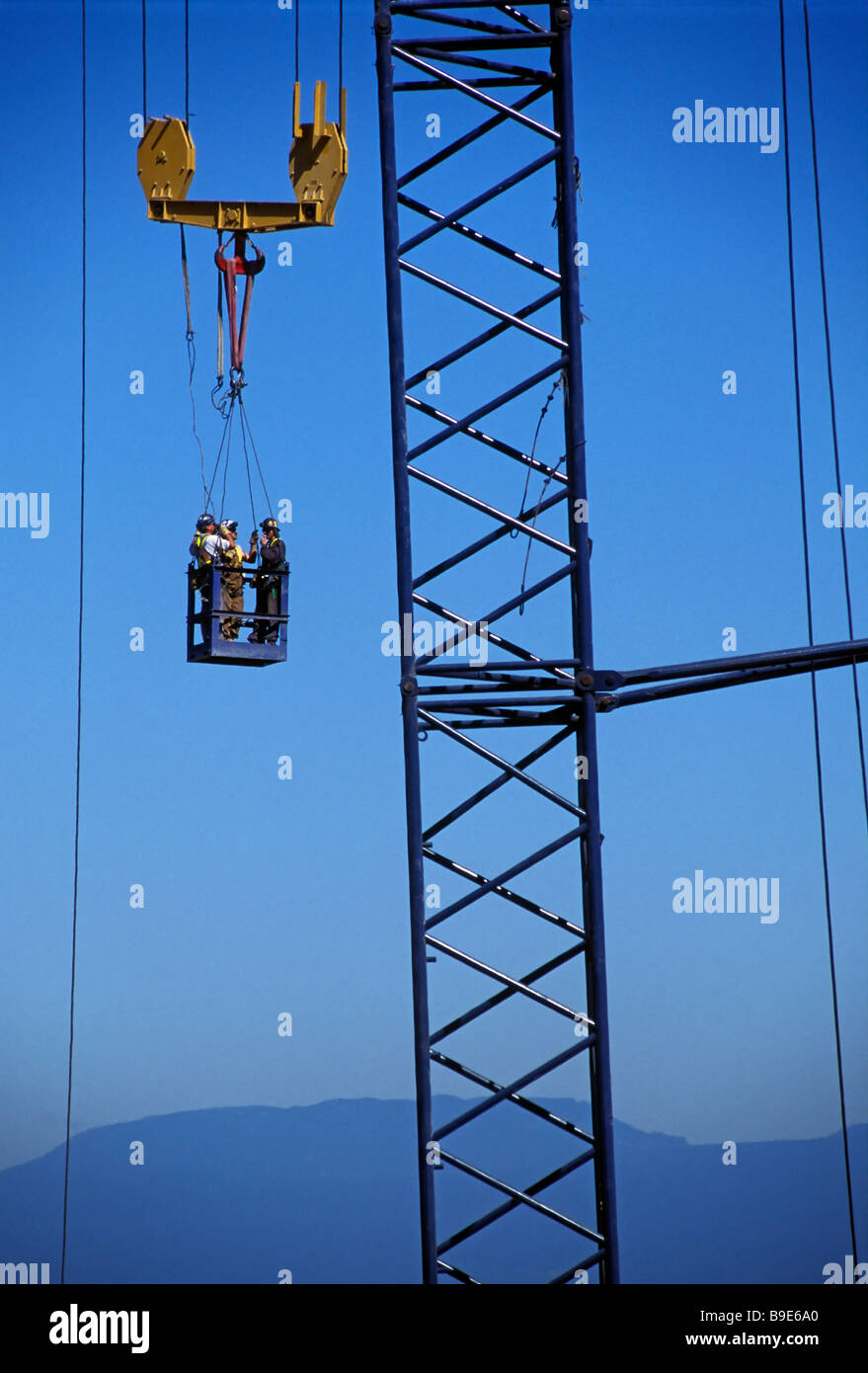 Going up Construction workers being lifted to rooftop construction site ...