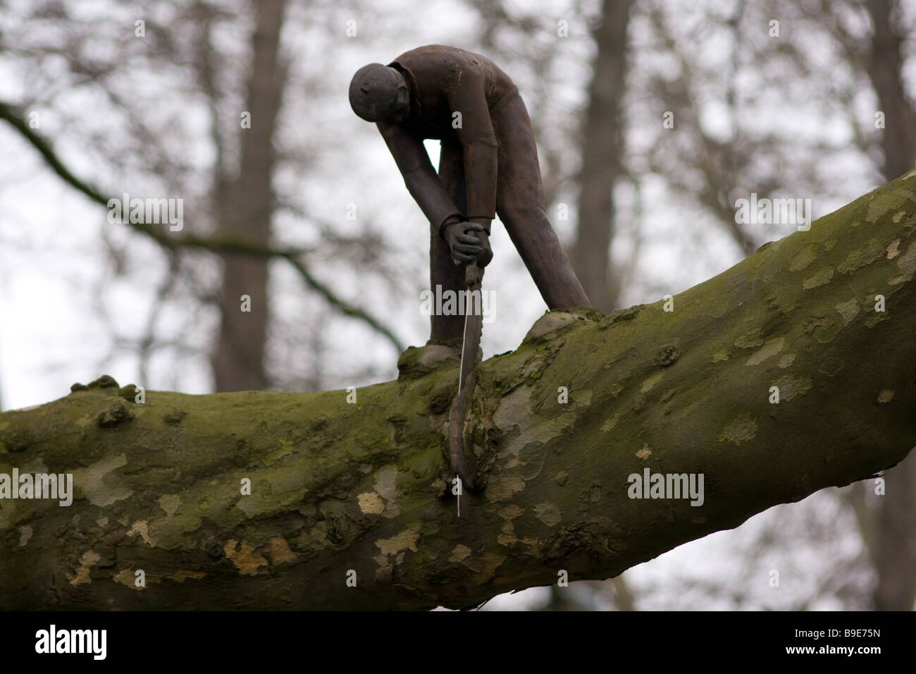 A man sculpture on a tree cuts the branch on which he is standing Stock ...