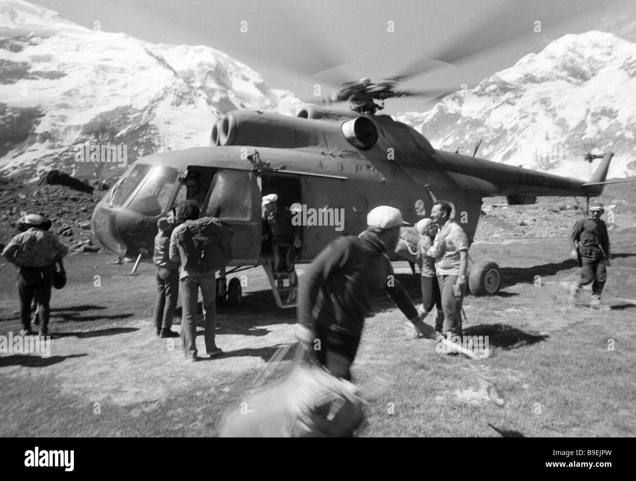 Mountain climbers disembarking from a helicopter at the foot of ...