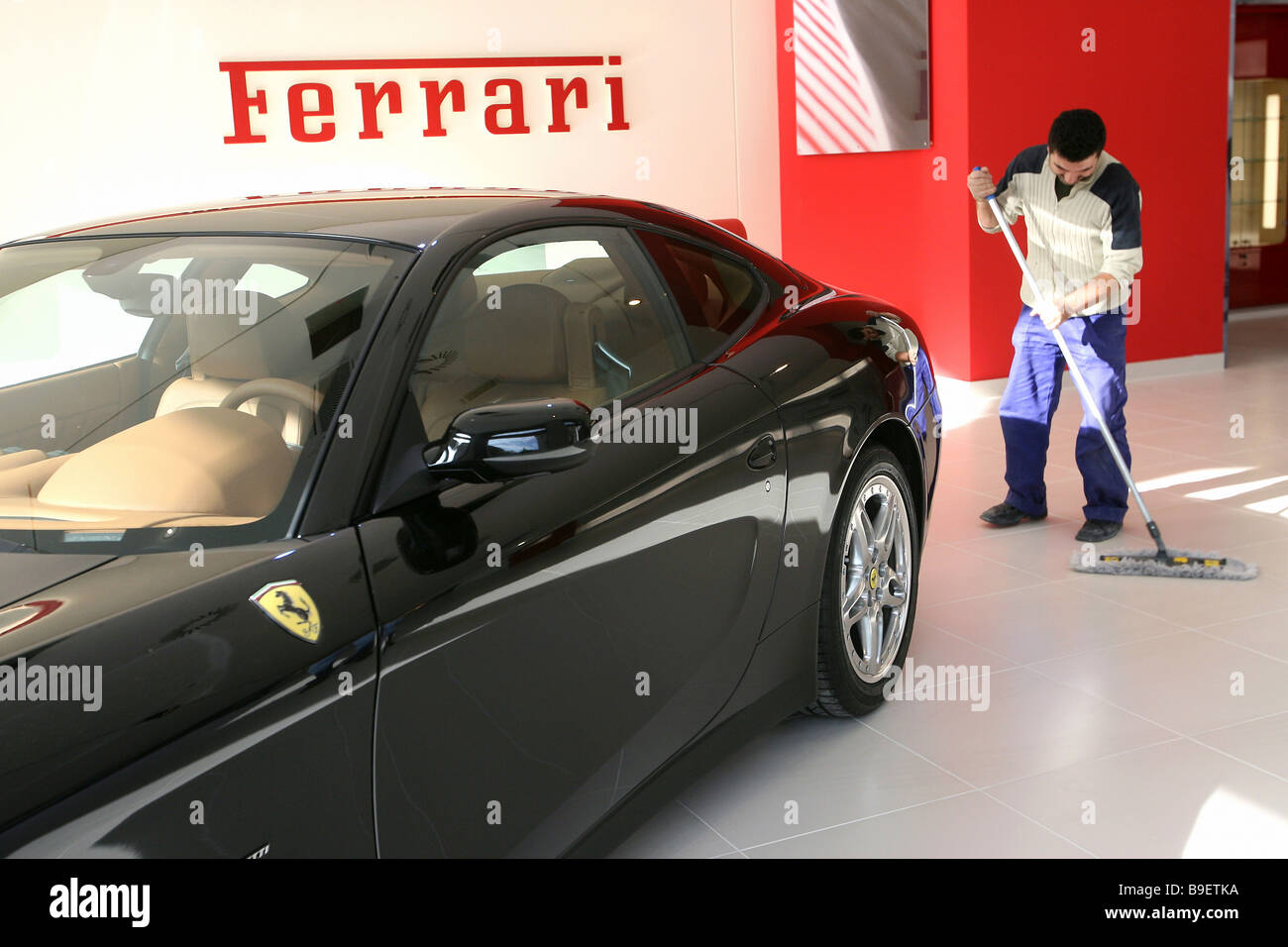 Man mopping floor next to a ferrari car Stock Photo - Alamy