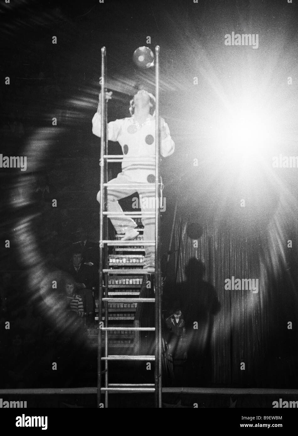 Circus performer balancing on a ladder while playing with a ball Stock ...