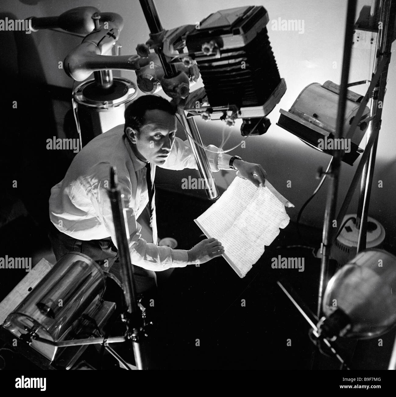 An expert studying a manuscript in the ancient document conservation ...