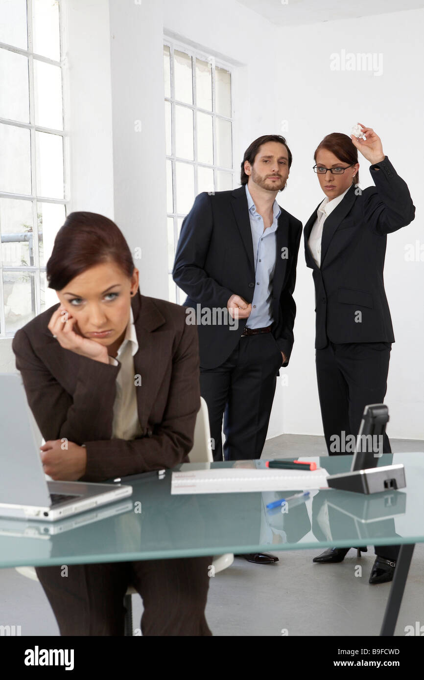 Businesswoman looking bored with two businesspeople standing in ...