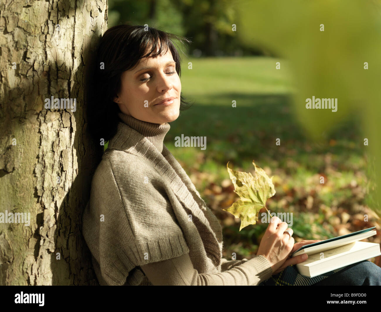 Close-up of mature woman resting against tree Stock Photo - Alamy