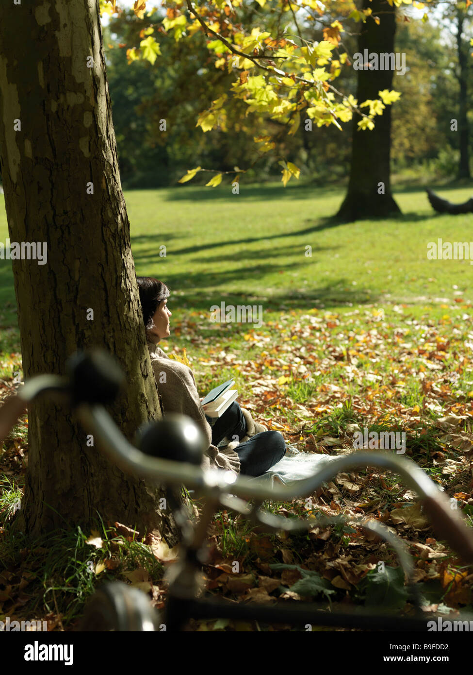 Rear view of mature woman resting against tree Stock Photo - Alamy