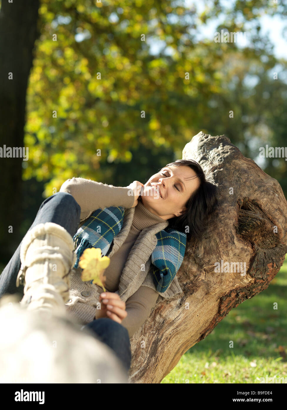 Mature woman resting on fallen tree and smiling Stock Photo - Alamy