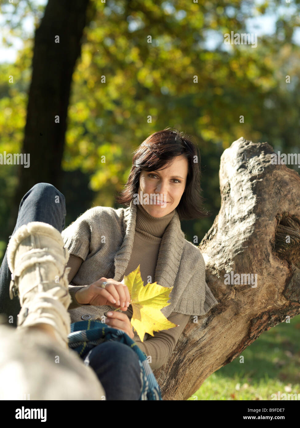 Portrait of mature woman sitting on fallen tree and smiling Stock Photo ...
