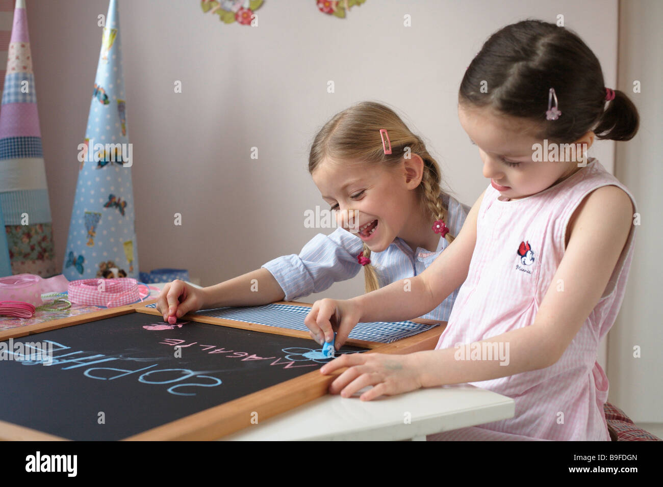 two girls writing on chalkboard Stock Photo - Alamy