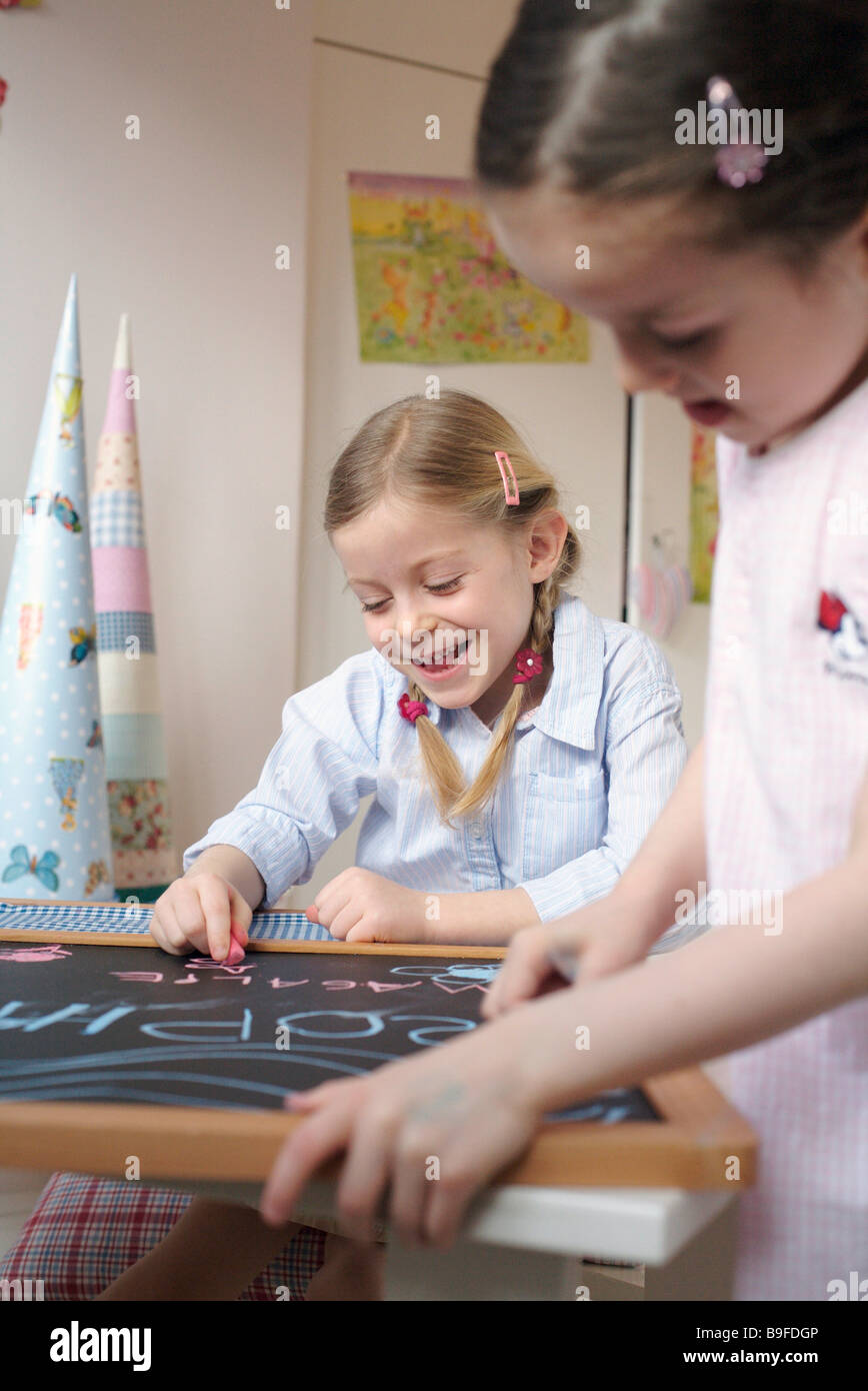 two girls writing on chalkboard Stock Photo - Alamy
