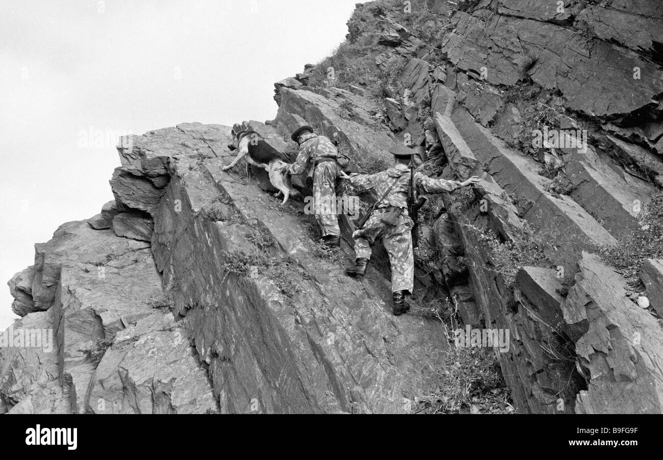 Frontier guards with a war dog are climbing a cliff Stock Photo - Alamy