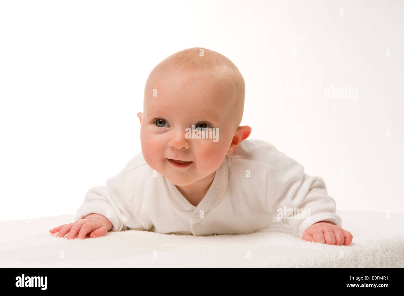 STUDIO SHOT OF BABY GIRL, 5 MONTHS, LYING ON FRONT, RESTING ON HANDS ...