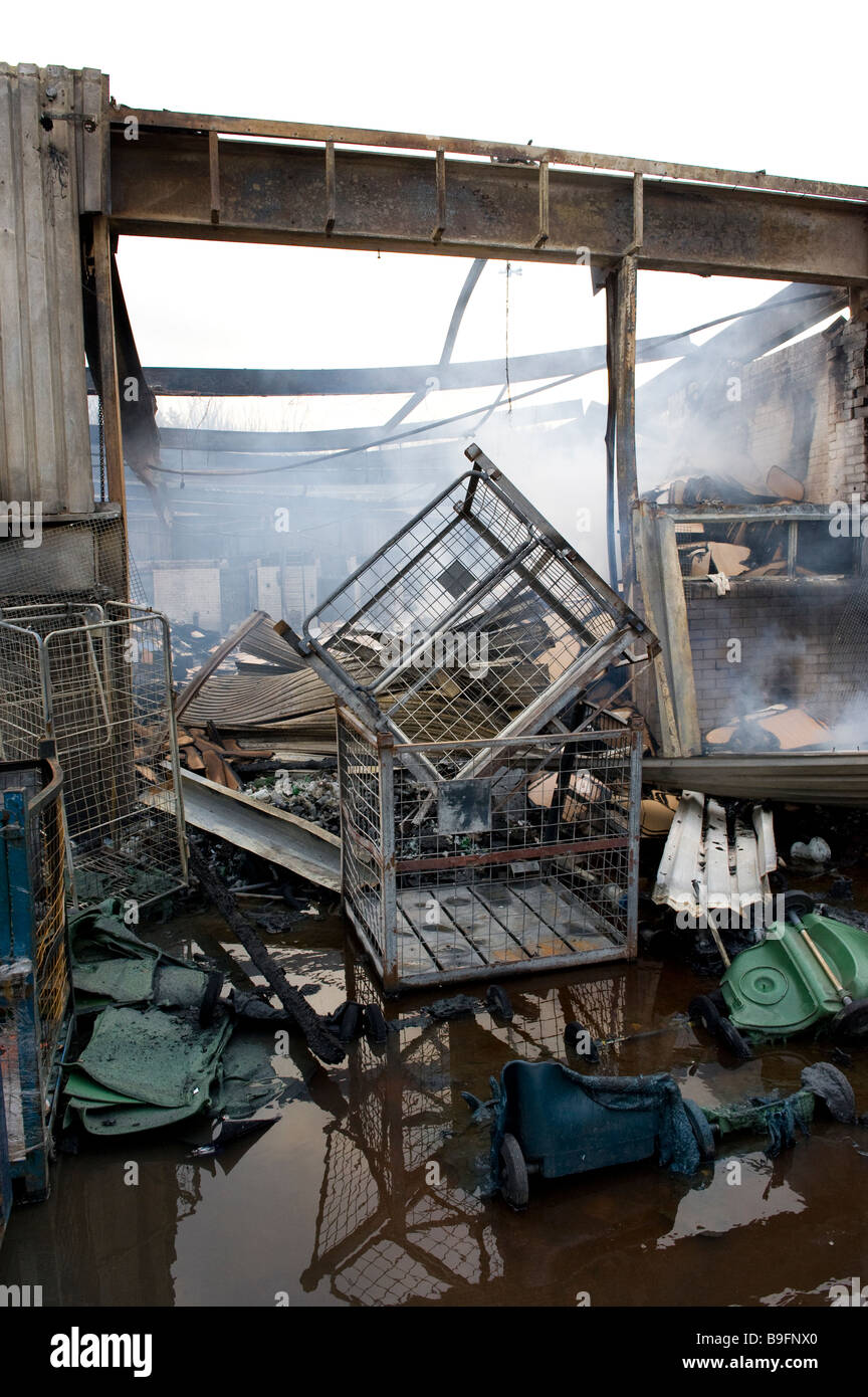 Burnt out factory industrial unit with melted wheelie bins outside ...