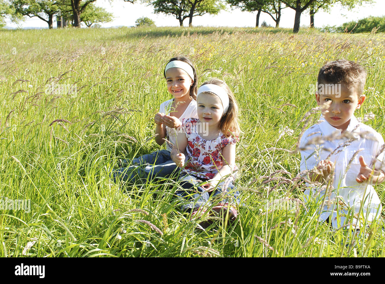 Children sitting meadow Stock Photo - Alamy