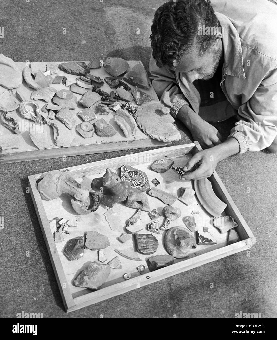 An archeologist studying details of ancient gold jewelry 11 century B C ...