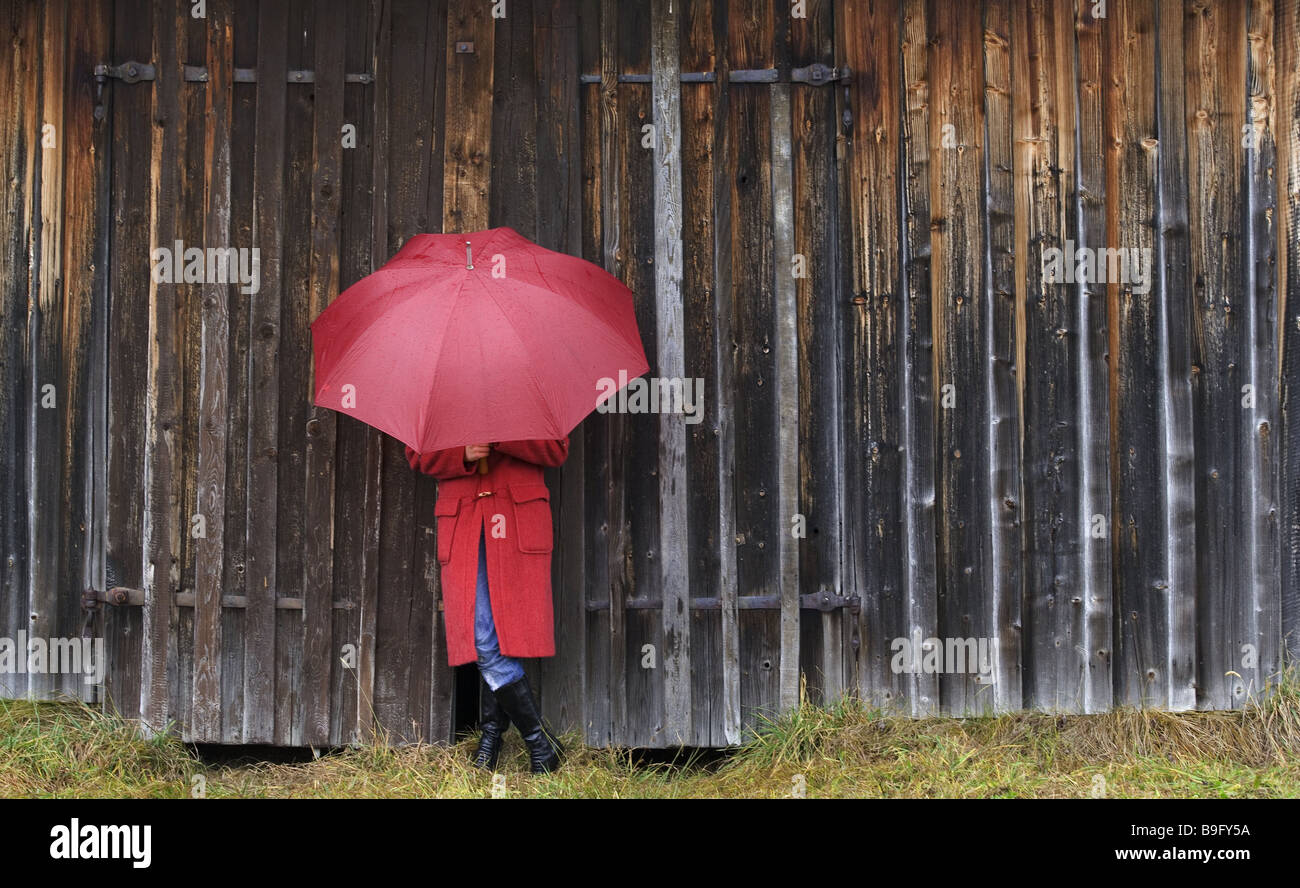 Barn woman detail coat boots stands face hidden umbrella red stretched ...