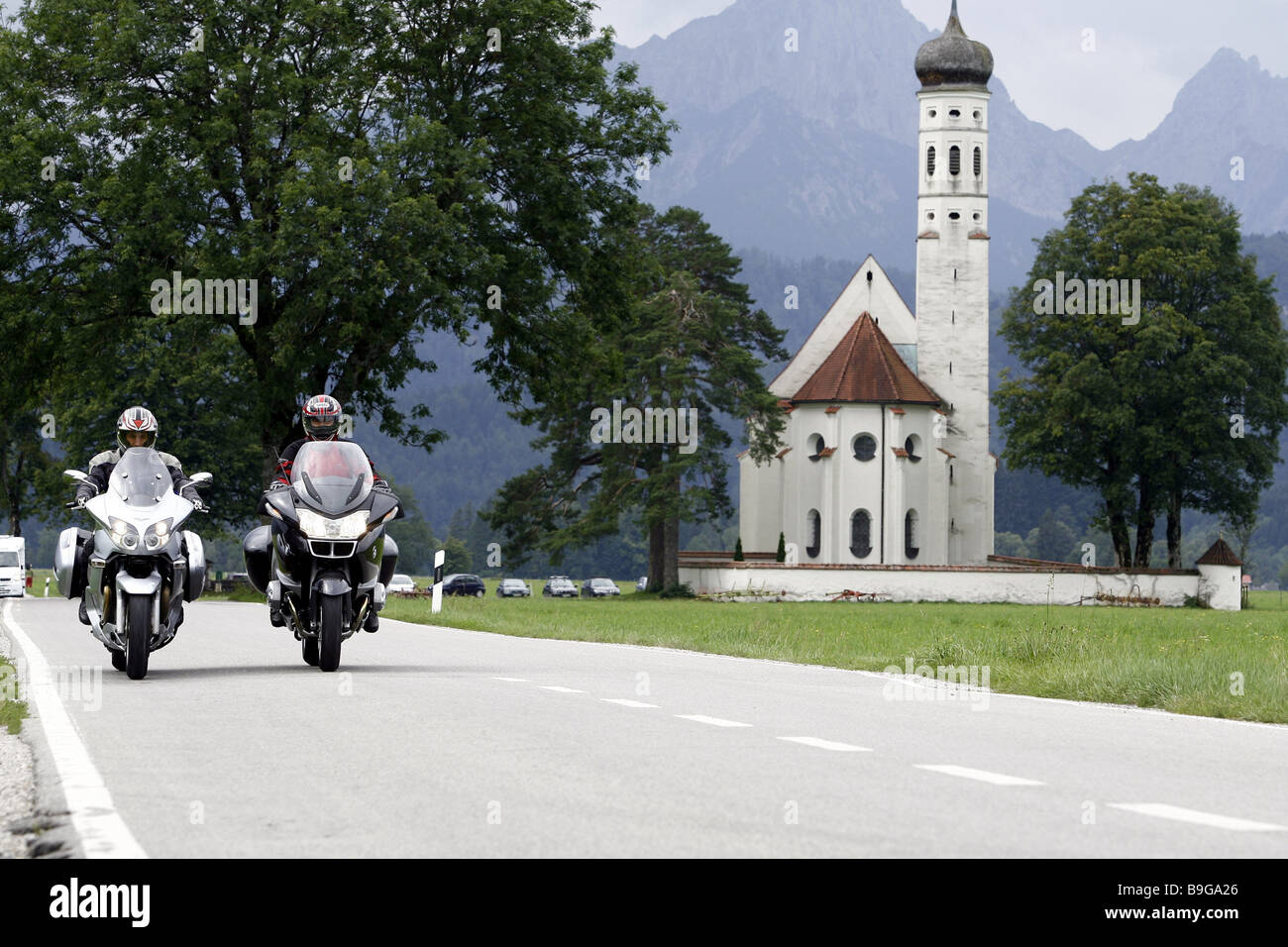 Country road motorcyclists two side by side background church streets ...