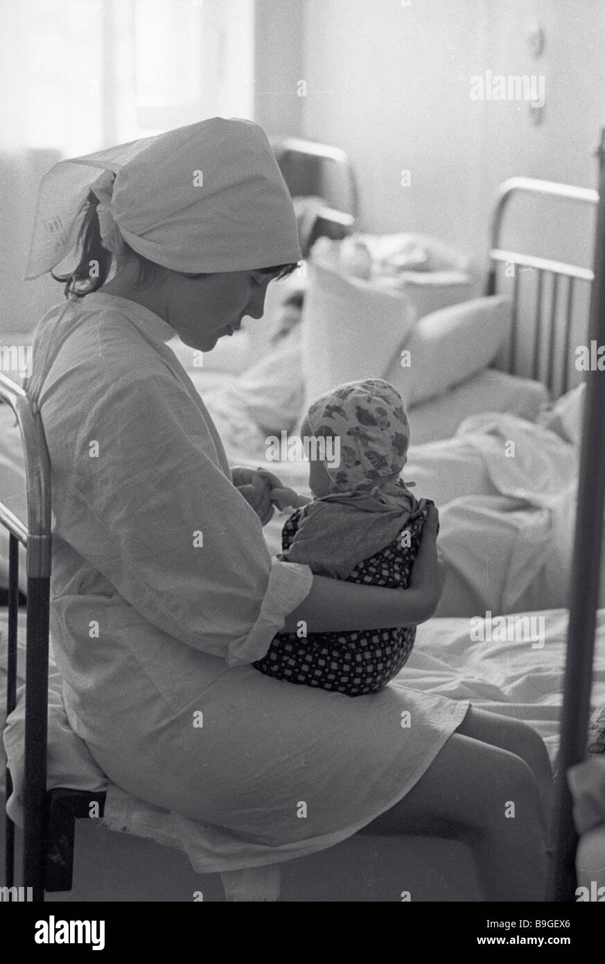 A medical attendant with a baby on her lap in the surgery department of ...