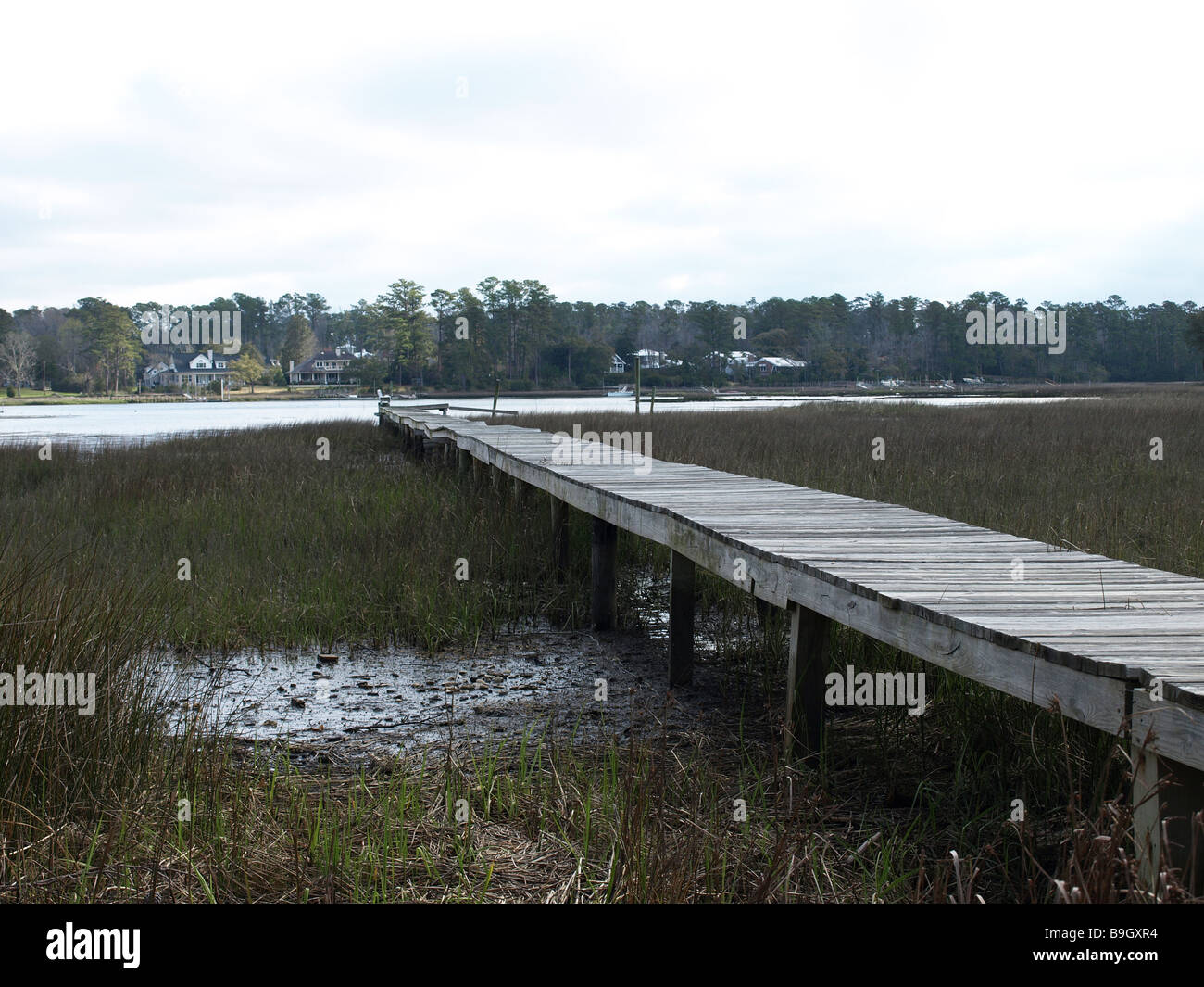 view of marsh river creek and long boat dock from shore in low ...