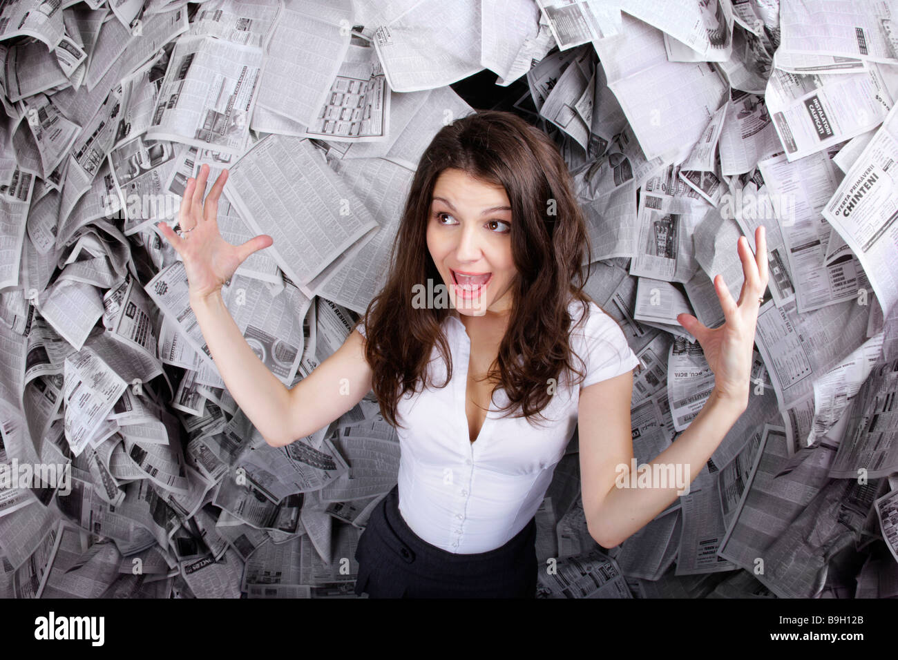 Business woman surrounded by newspapers expressing stress caused by too ...