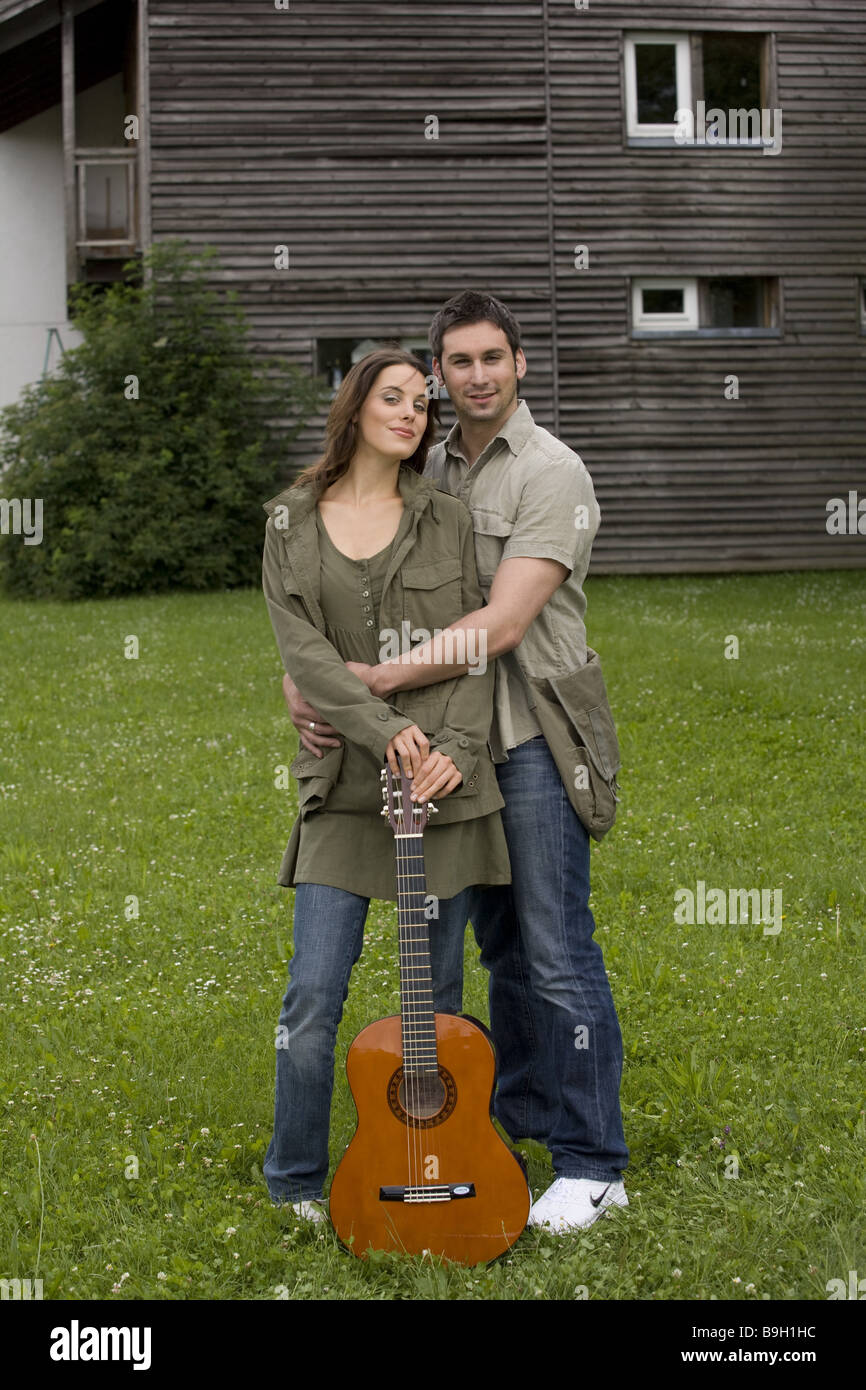 Mate stands smiling embraces garden guitar music-instrument full-length ...