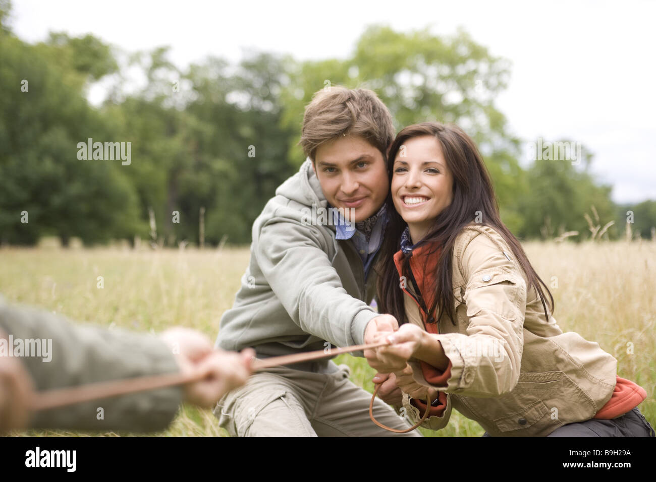 Mate tug-of-war rope pulls smiling leisure time nature outside 20-30 ...