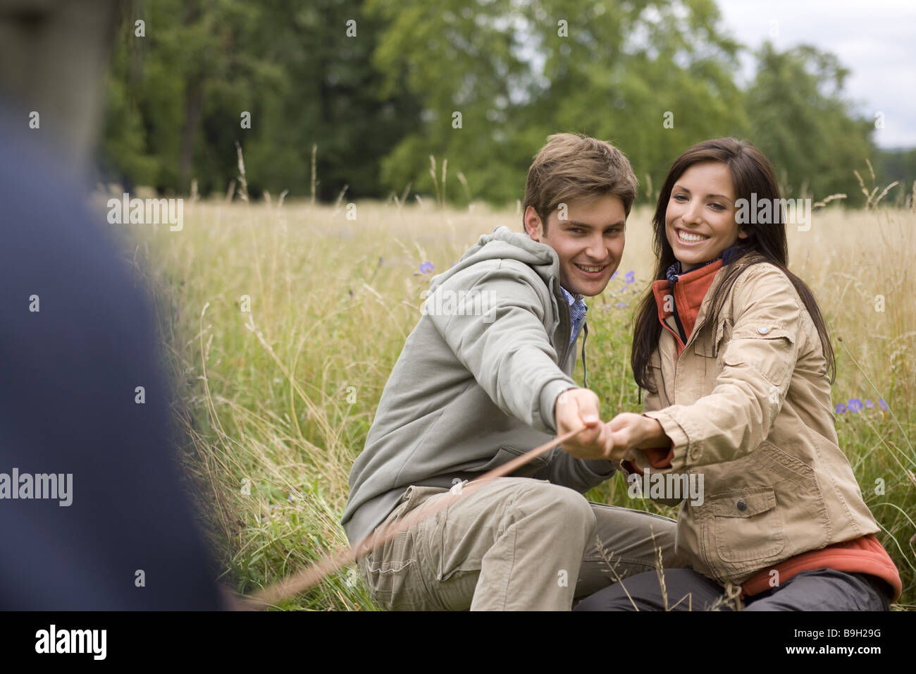 Mate tug-of-war rope pulls smiling leisure time nature outside 20-30 ...