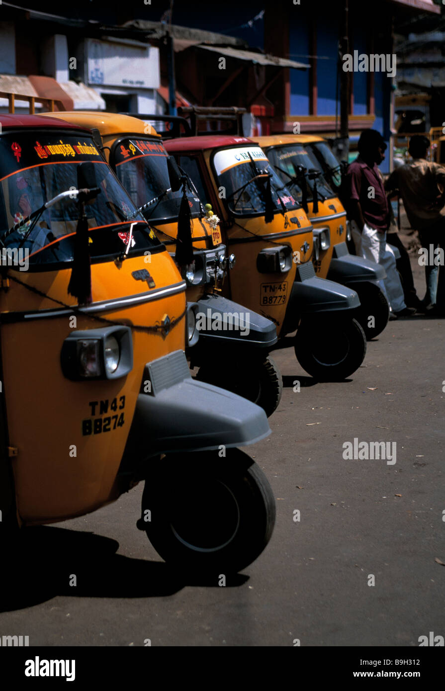 three wheeled transport vehicles sitting on a street in an indian city ...