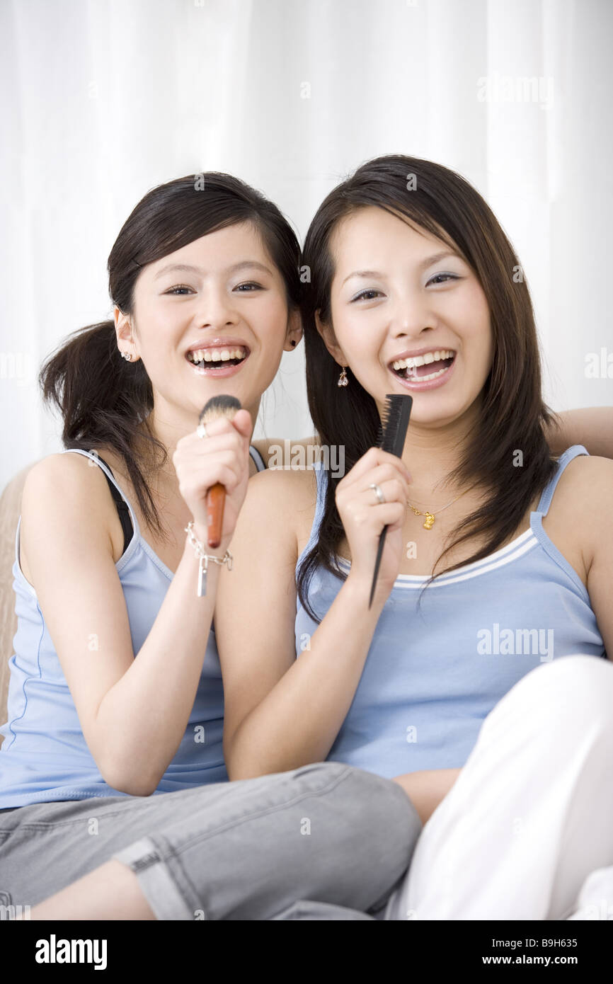Two young women holding microphone singing smiling portrait Stock Photo ...