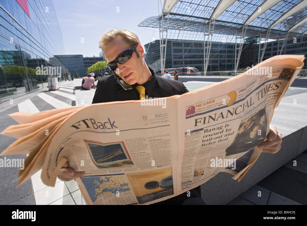Businessman newspaper cell phone reads telephones outside Stock Photo ...