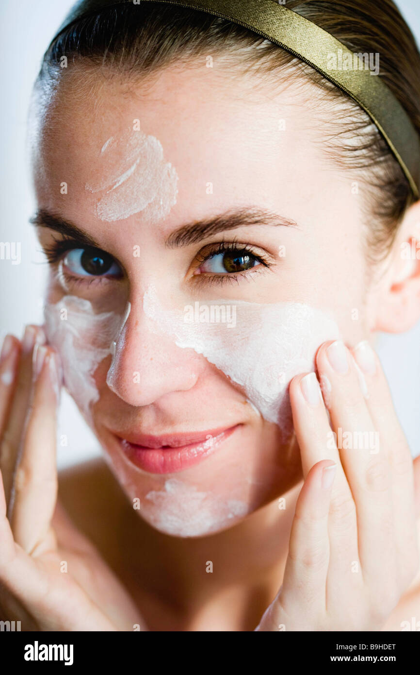 Woman putting face mask on Stock Photo - Alamy