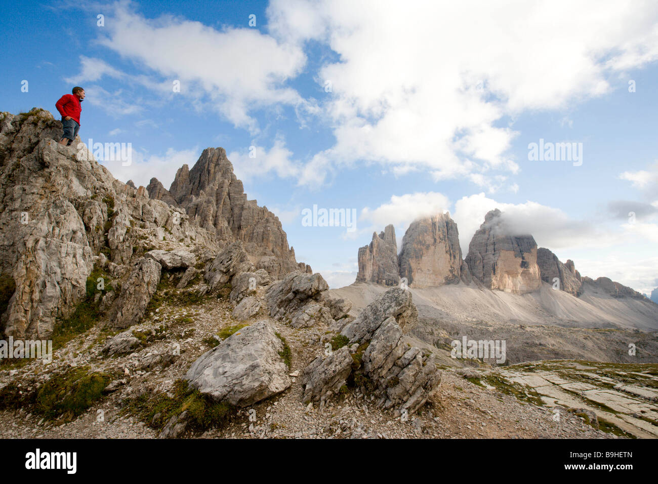 Man standing on rocks looking at peaks Stock Photo - Alamy