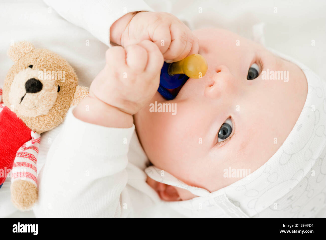 Baby nibbling on pacifier Stock Photo - Alamy