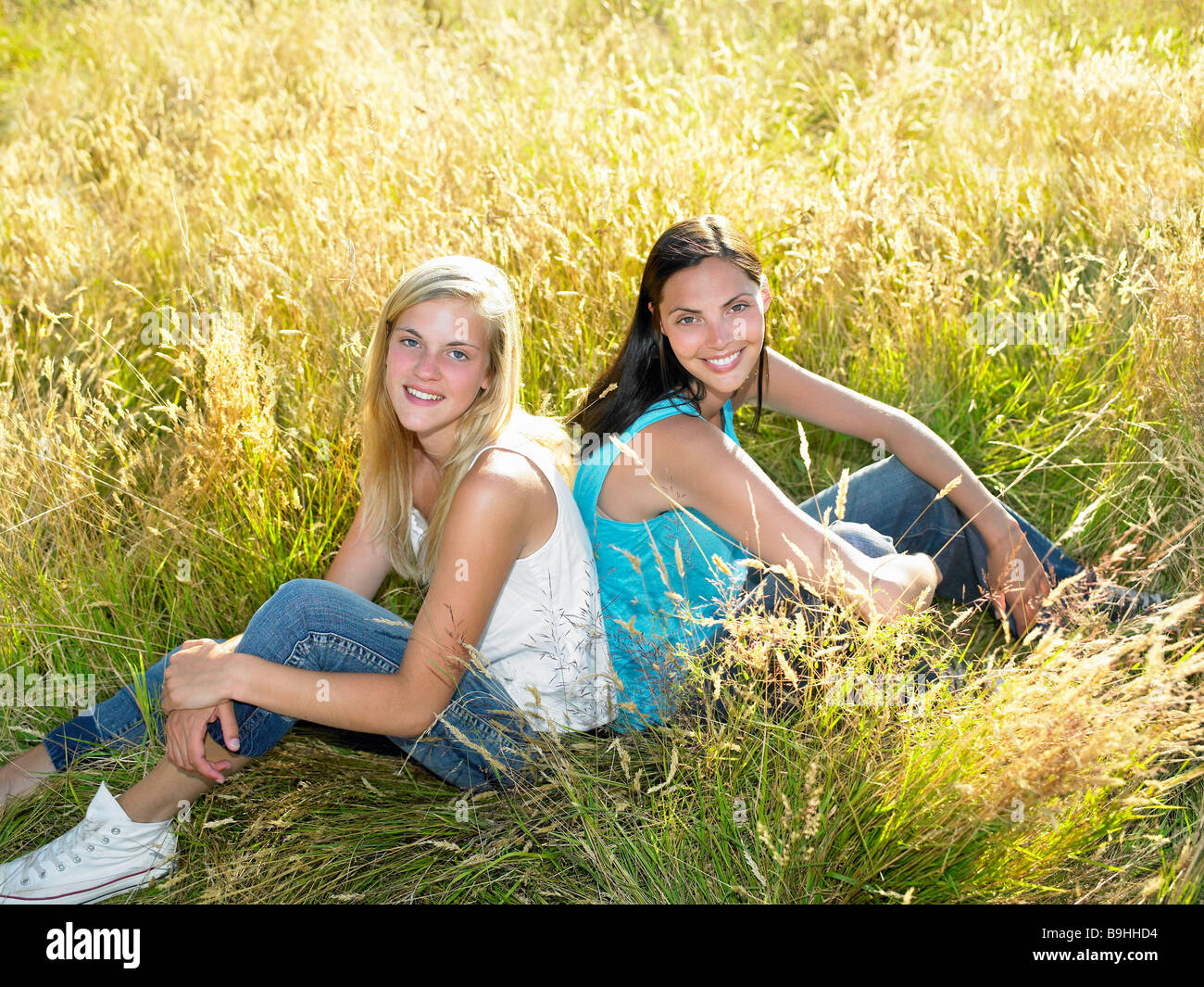 Girls seated in a field Stock Photo - Alamy