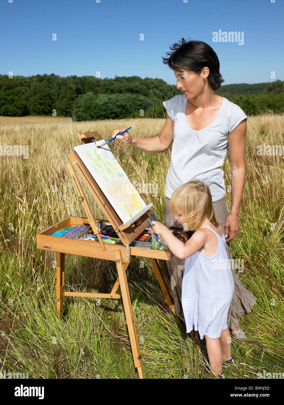 Mother and daughter painting in a field Stock Photo - Alamy